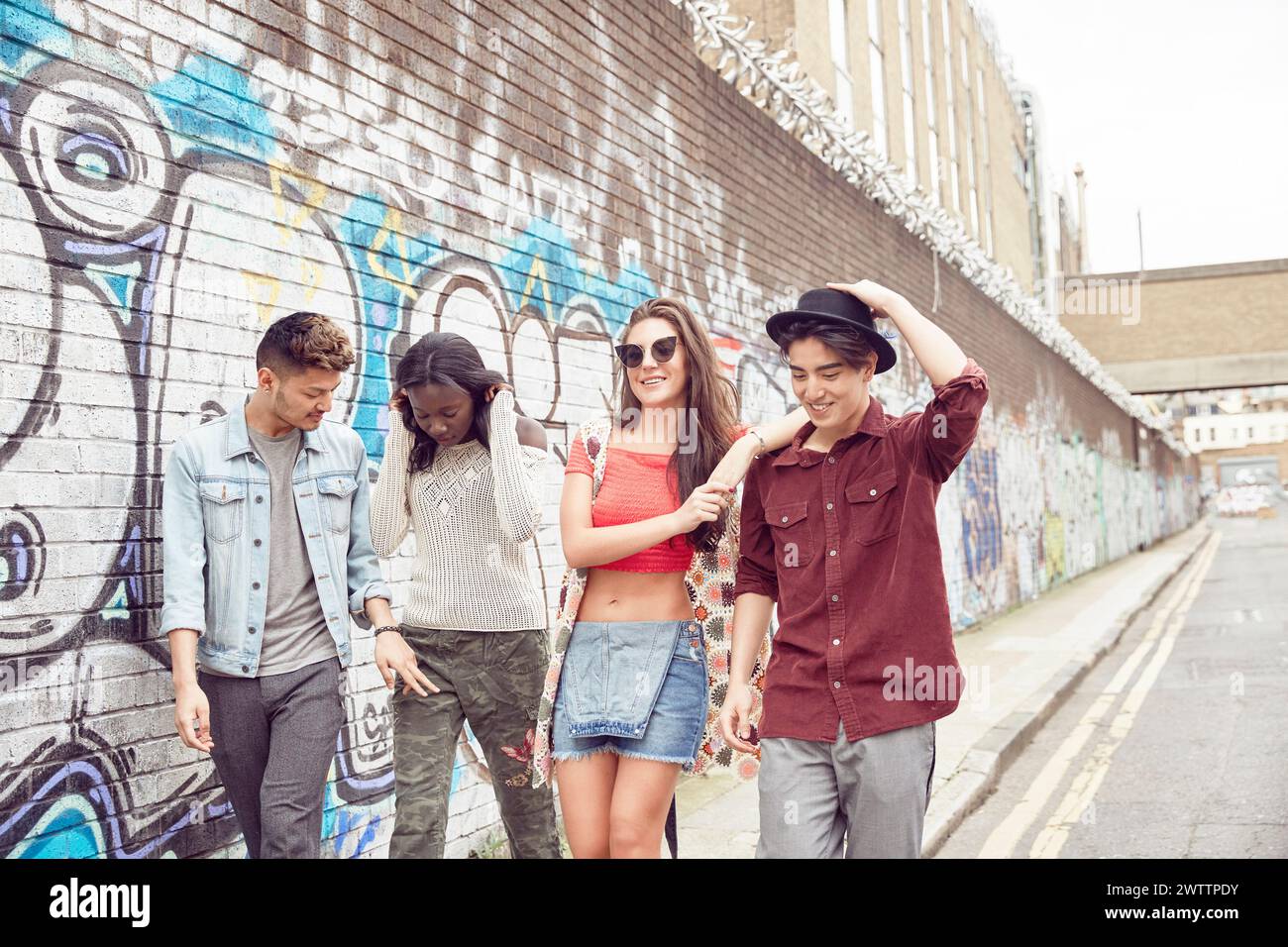 Friends walking by a graffiti wall Stock Photo - Alamy