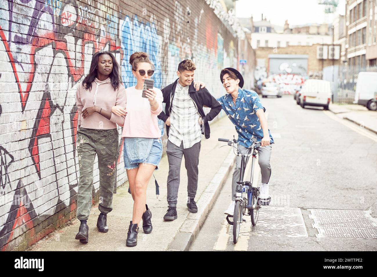 Friends walking together on a graffiti-lined street Stock Photo - Alamy