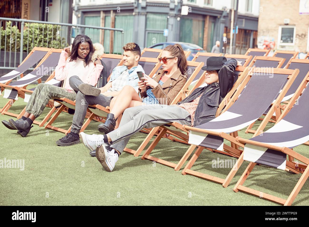 Group of friends relaxing on deck chairs in an urban setting Stock ...