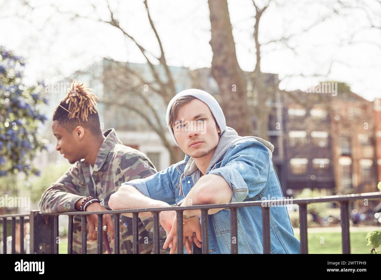 Two young men leaning on a fence outdoors Stock Photo - Alamy