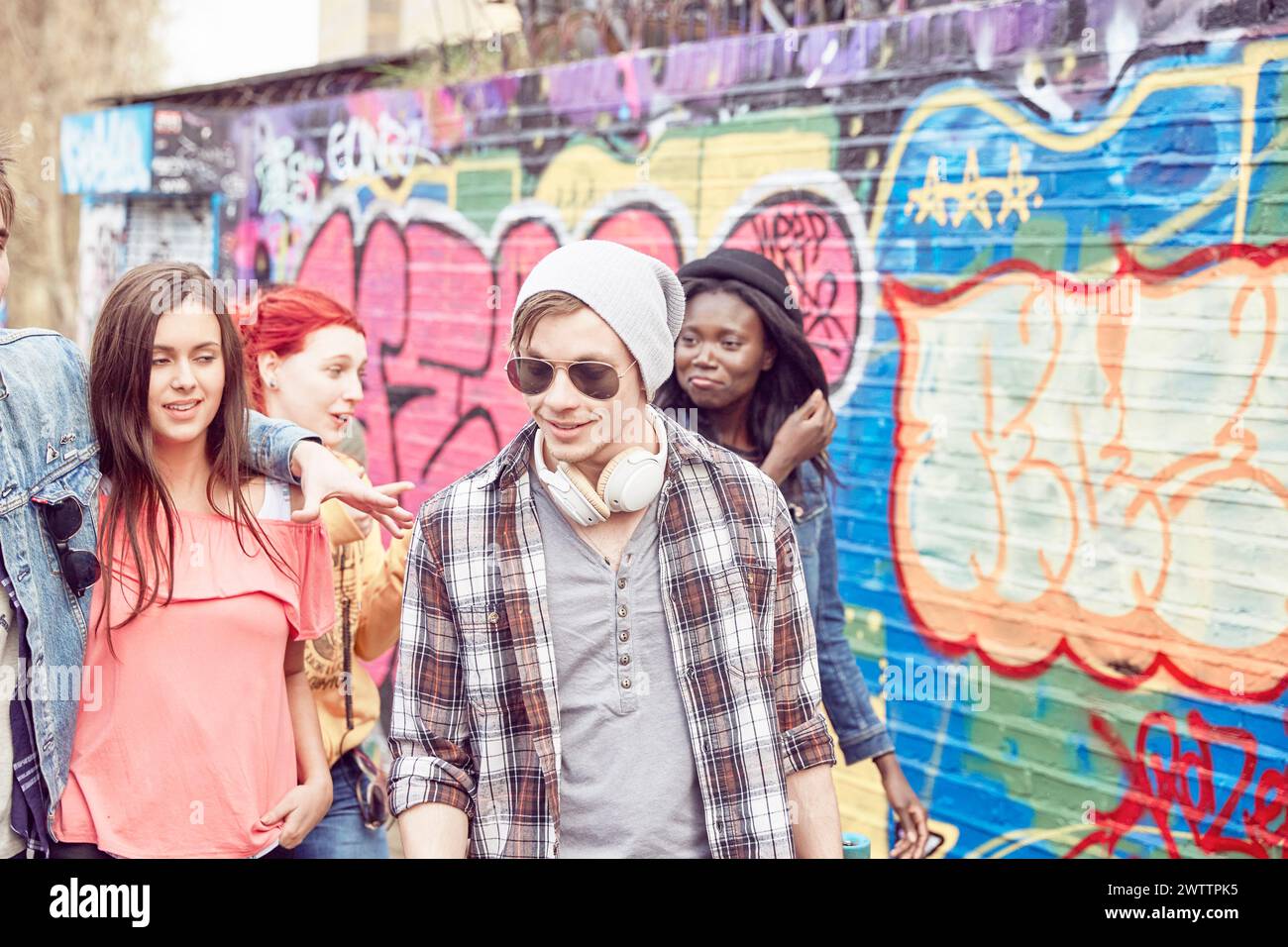 Friends hanging out by a graffiti wall Stock Photo - Alamy