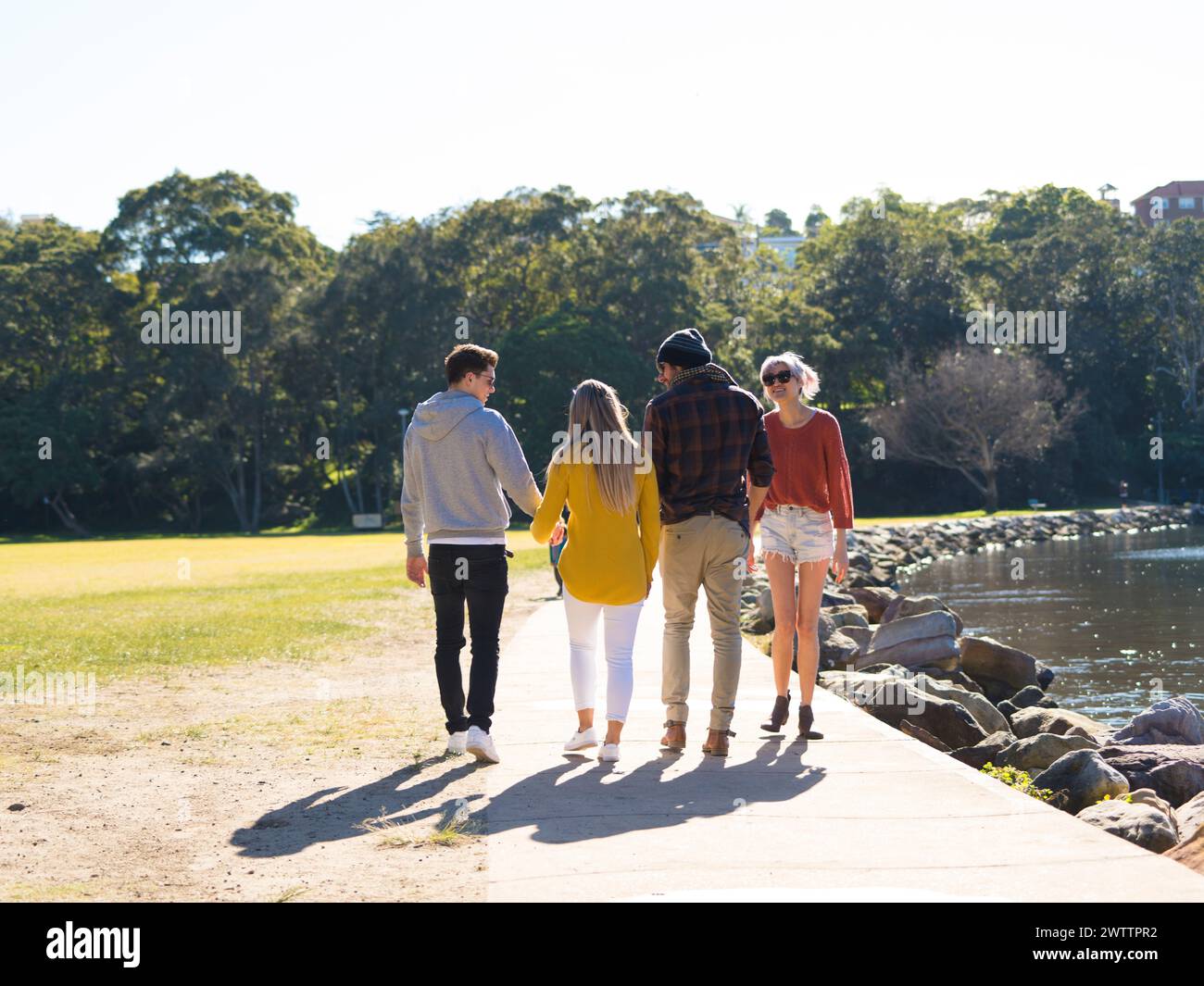 Four friends walking on a path in a park Stock Photo - Alamy