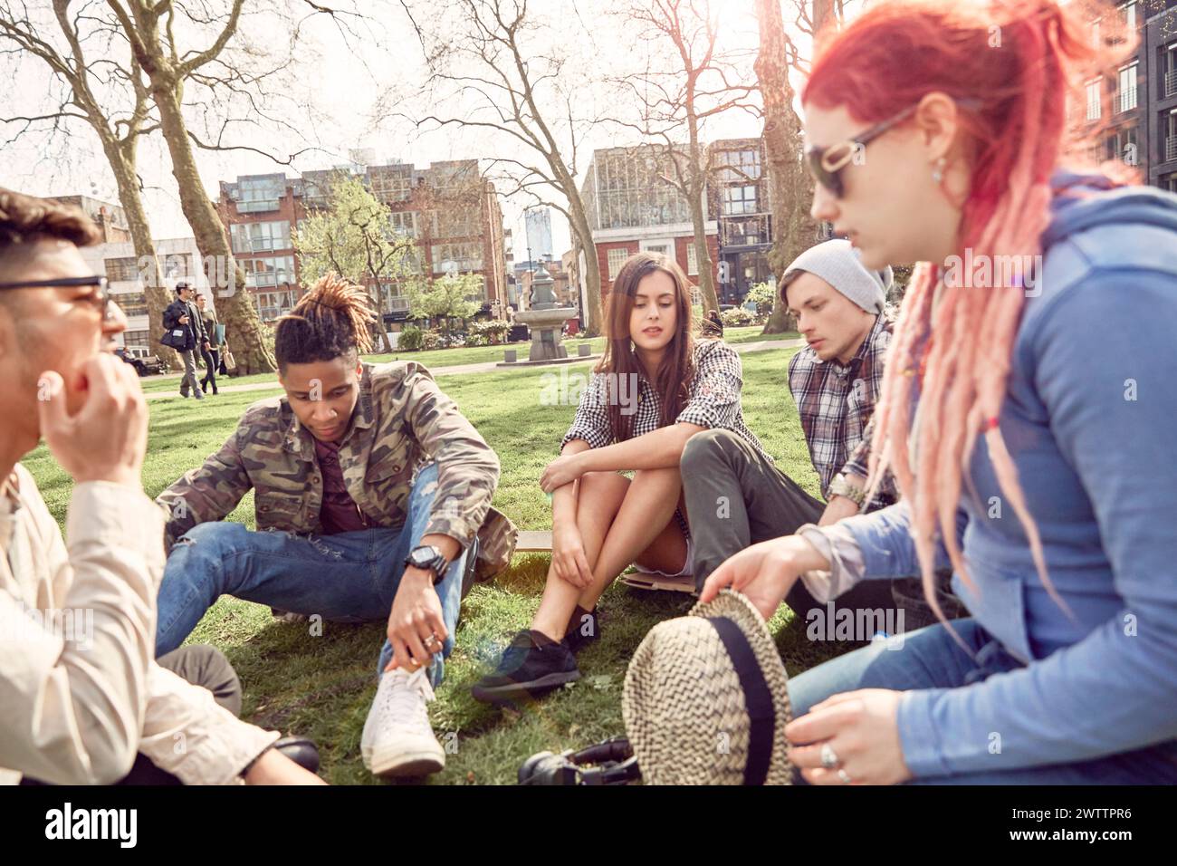 Group of friends sitting on grass in a park Stock Photo - Alamy