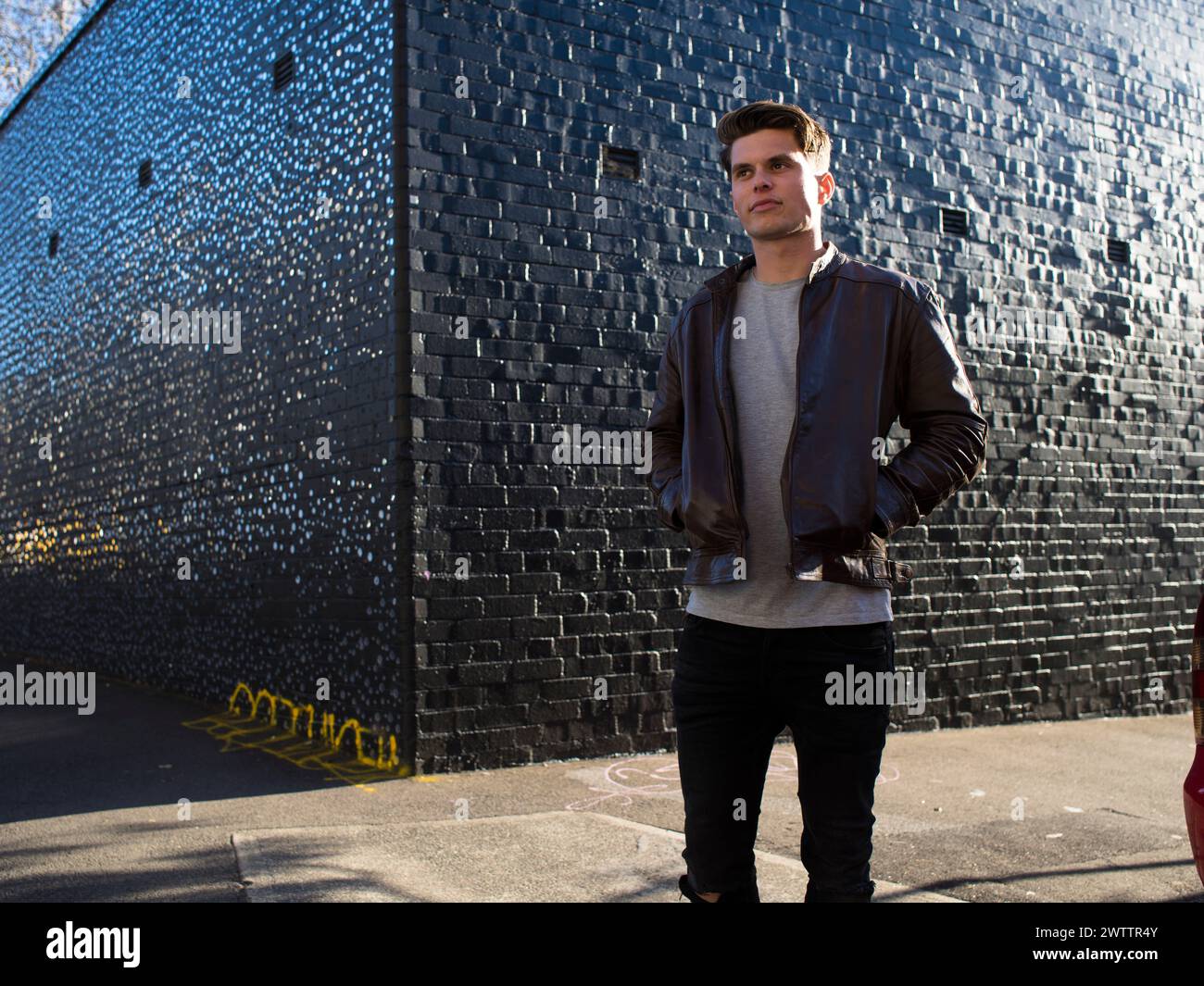 Young man standing front wall hi-res stock photography and images - Alamy