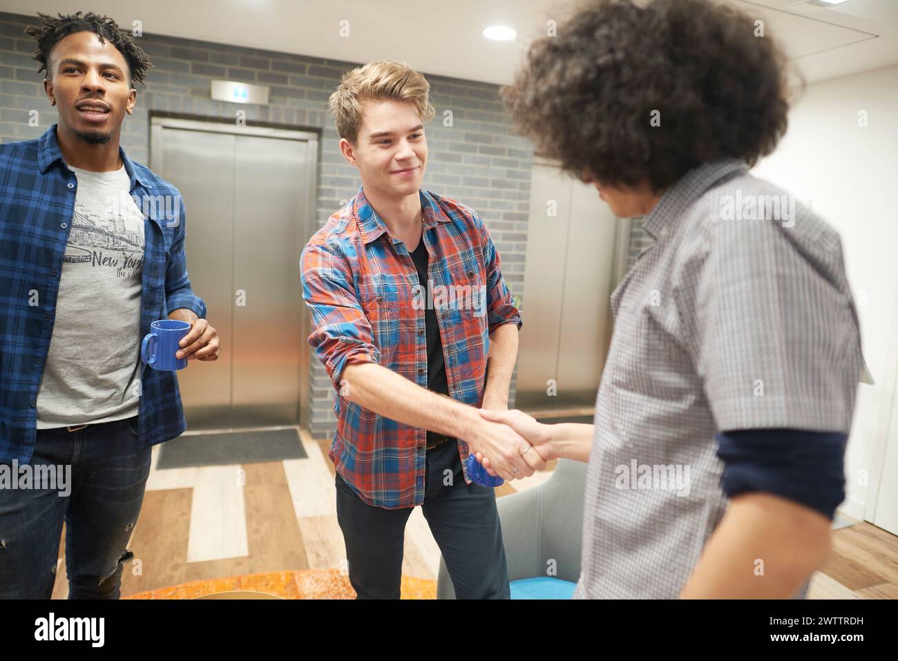 Men shaking hands in an office hallway Stock Photo - Alamy