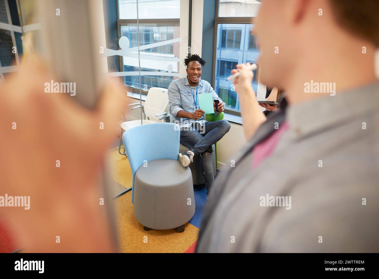 Two people talking in a brightly lit office space Stock Photo - Alamy
