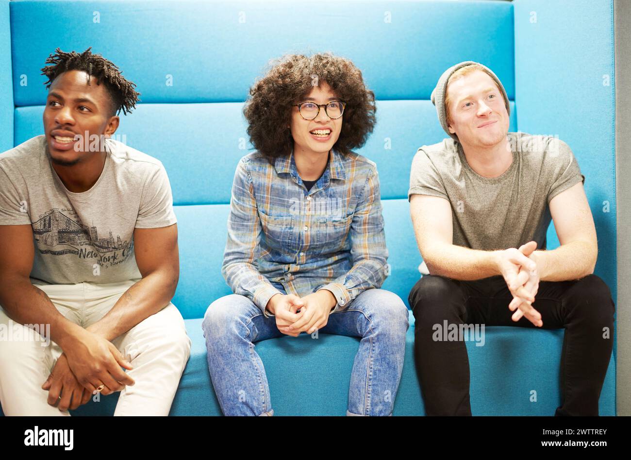 Three people sitting together on a blue couch Stock Photo - Alamy