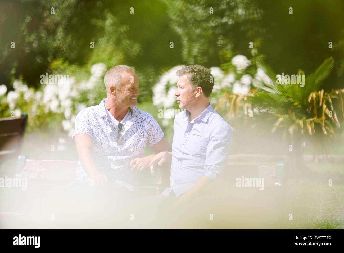 Two men chatting on a park bench Stock Photo - Alamy