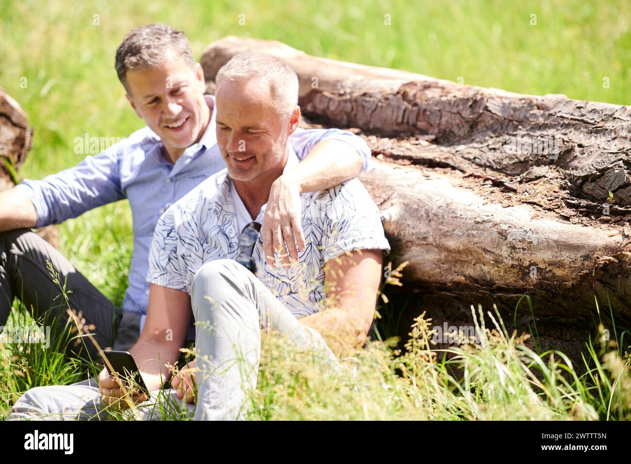 Two men smiling and sitting together outdoors Stock Photo - Alamy