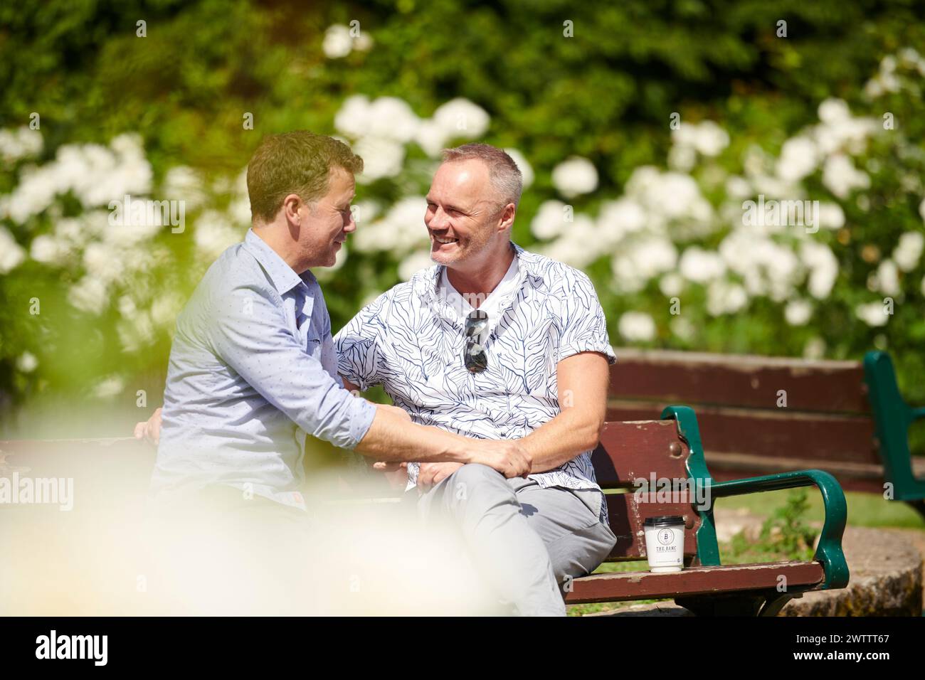 Two men chatting on a park bench Stock Photo - Alamy