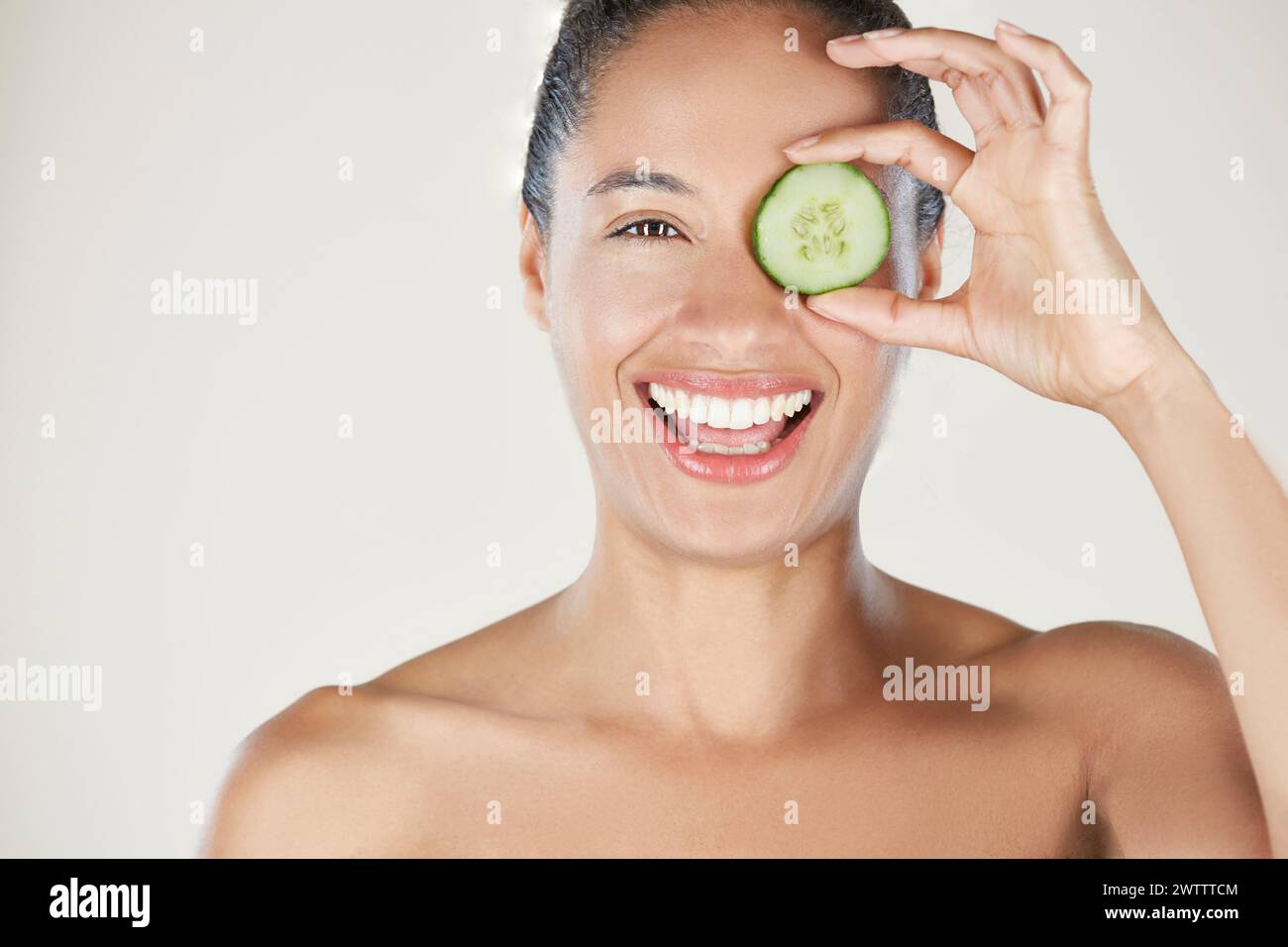 Woman smiling with a cucumber slice over her eye Stock Photo - Alamy