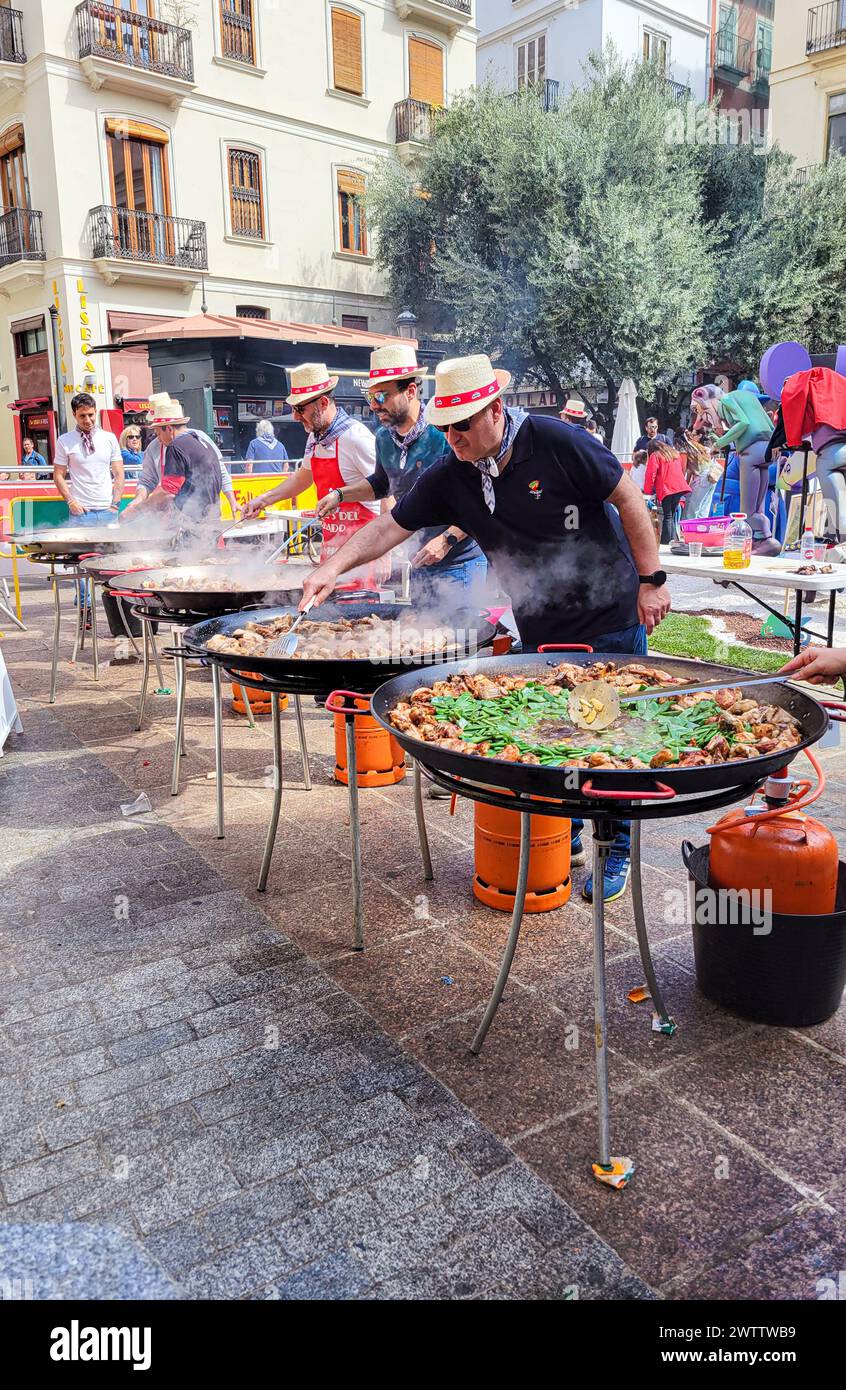 Valencia, Spain, March 2024: Group of people cooking communal paellas ...
