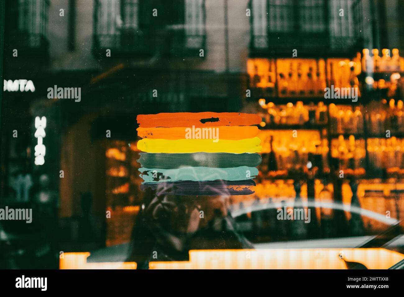 Rainbow flag drawn with different colors on a glass front door of a ...