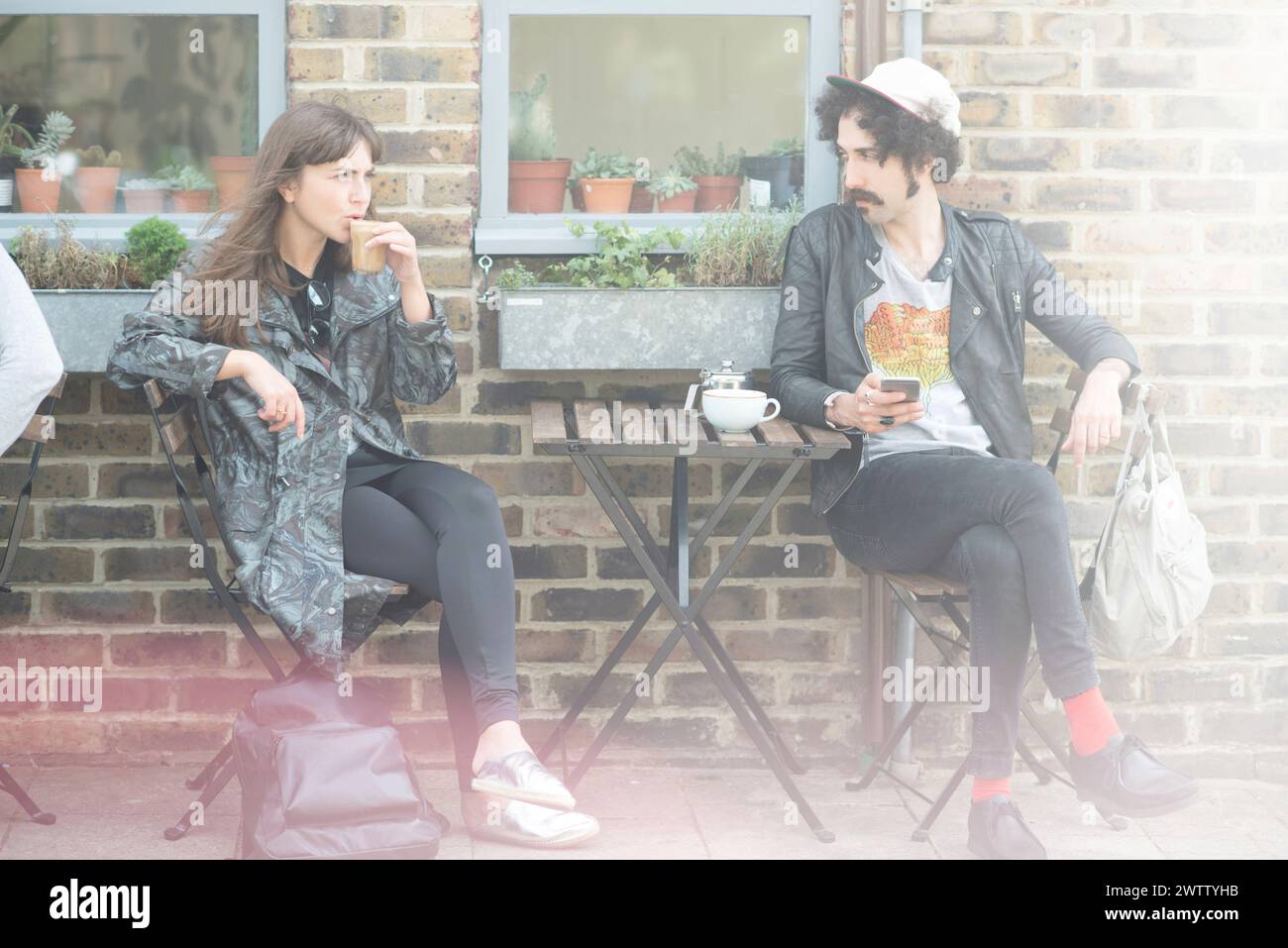Two people sitting at a café table outdoors Stock Photo - Alamy