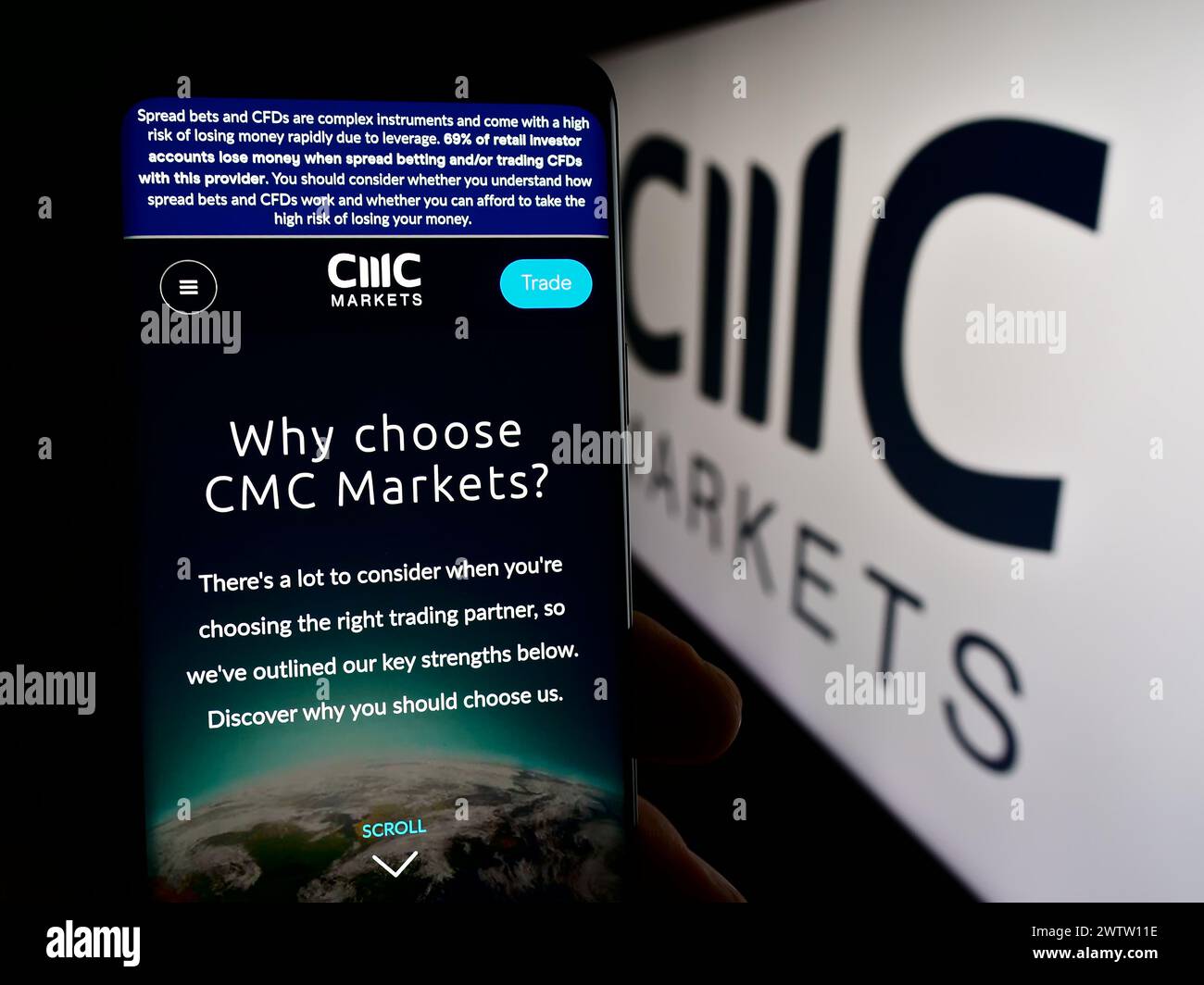 Person holding cellphone with webpage of British financial services company CMC Markets plc in ...