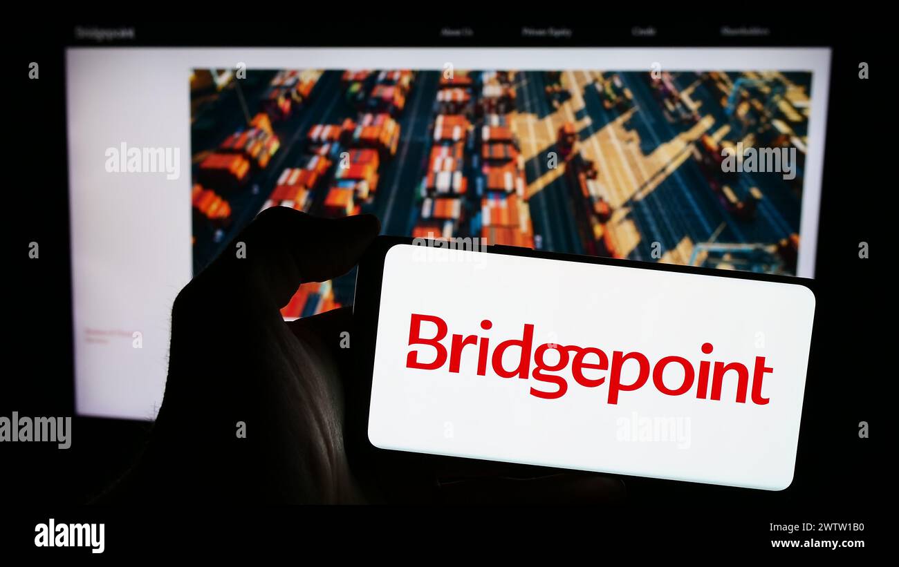 Person holding mobile phone with logo of British investment company Bridgepoint Group plc in ...