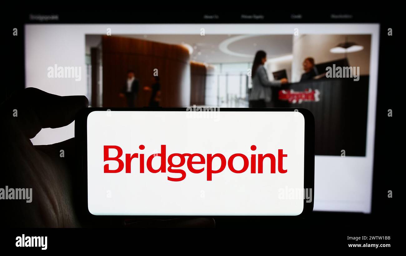 Person holding cellphone with logo of British investment company Bridgepoint Group plc in front ...