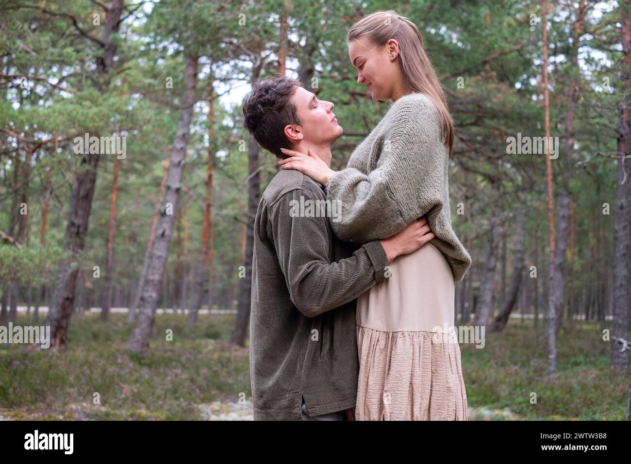 Man and woman in an affectionate embrace in a pine forest. Its a scene ...