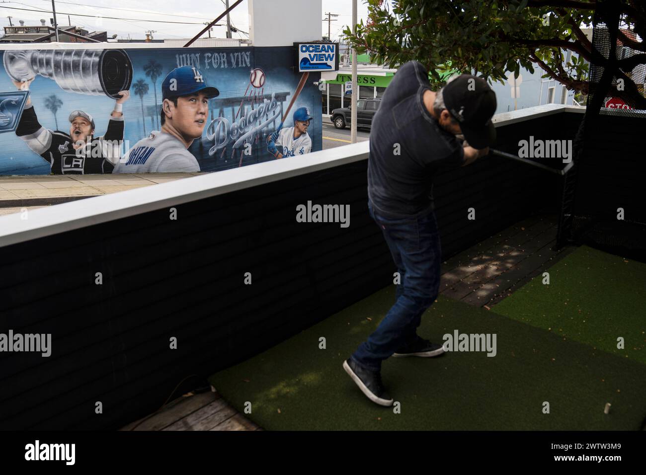 Terry Nolan works on his golf swing on his patio as a mural of Los ...