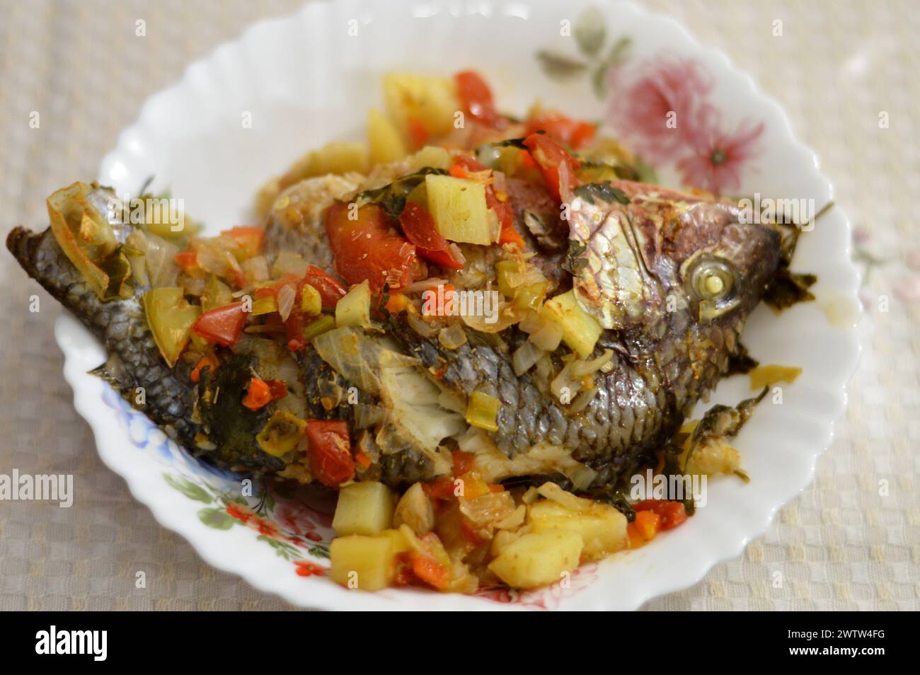 Baked tilapia fish Oreochromis niloticus mixed with slices of tomatoes ...