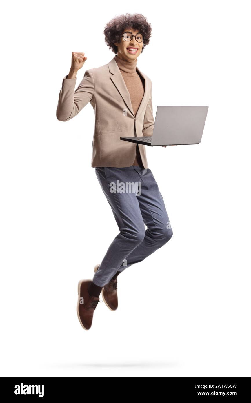 Excited young man jumping with a laptop computer isolated on white ...