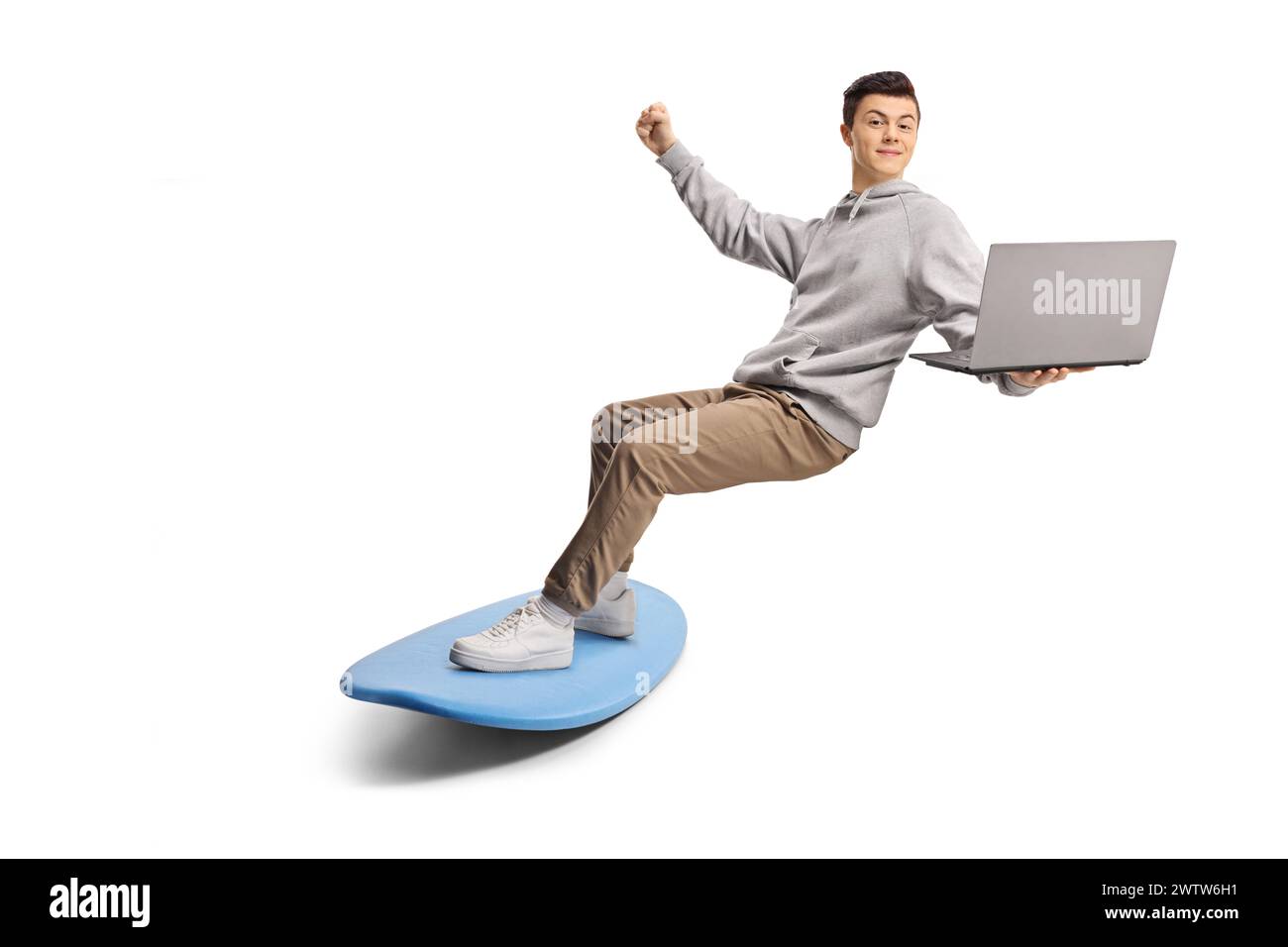 Male teenager surfing on a surfboard and holding a laptop computer ...