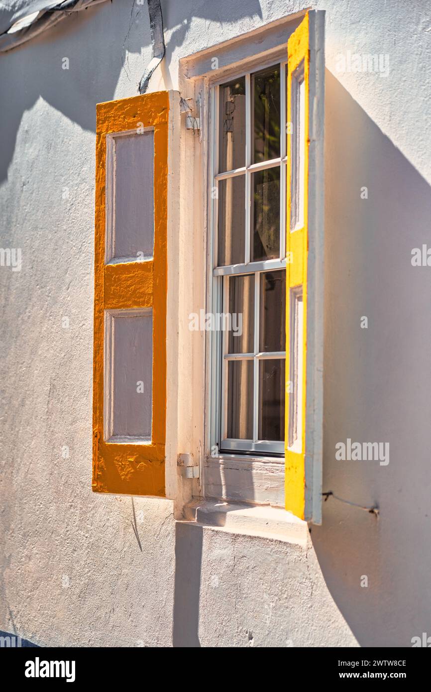 A striking image of a sunlit traditional window with orange shutters ...