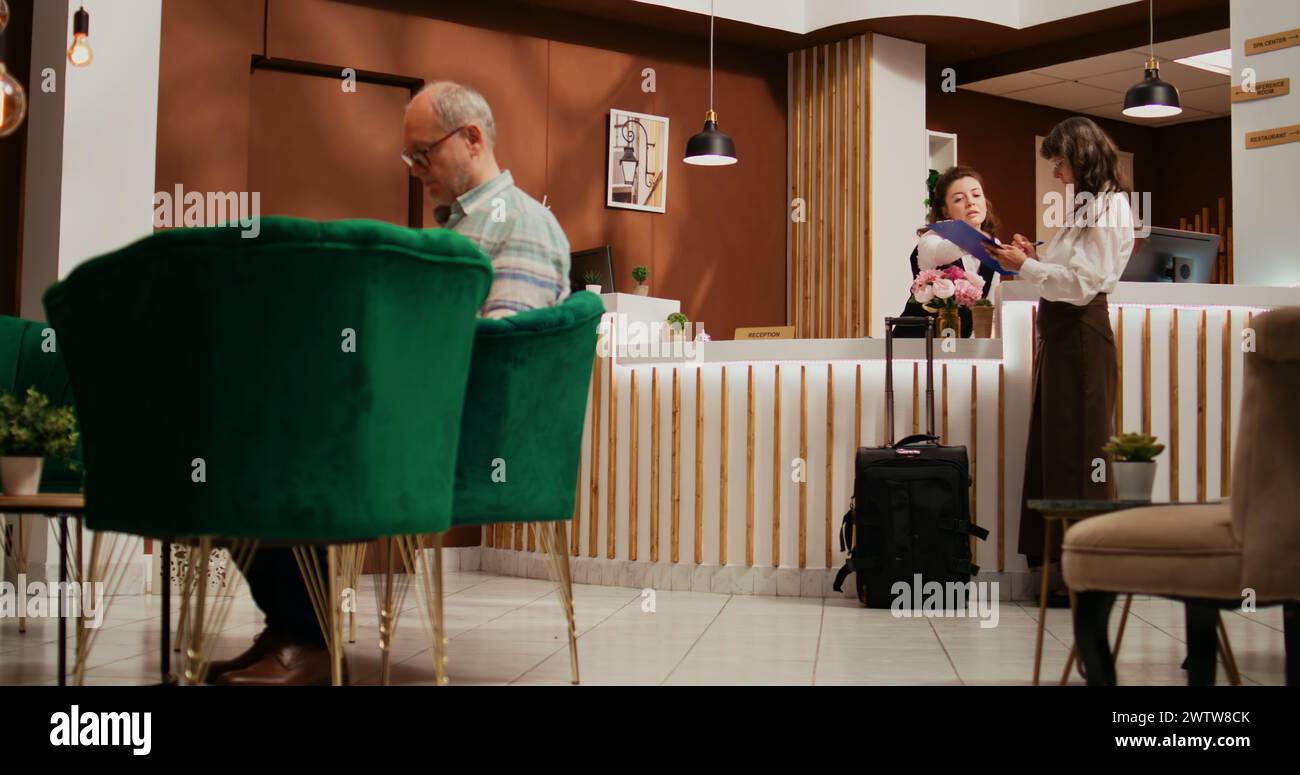 Hotel guest signing registration forms and finish with check in process ...