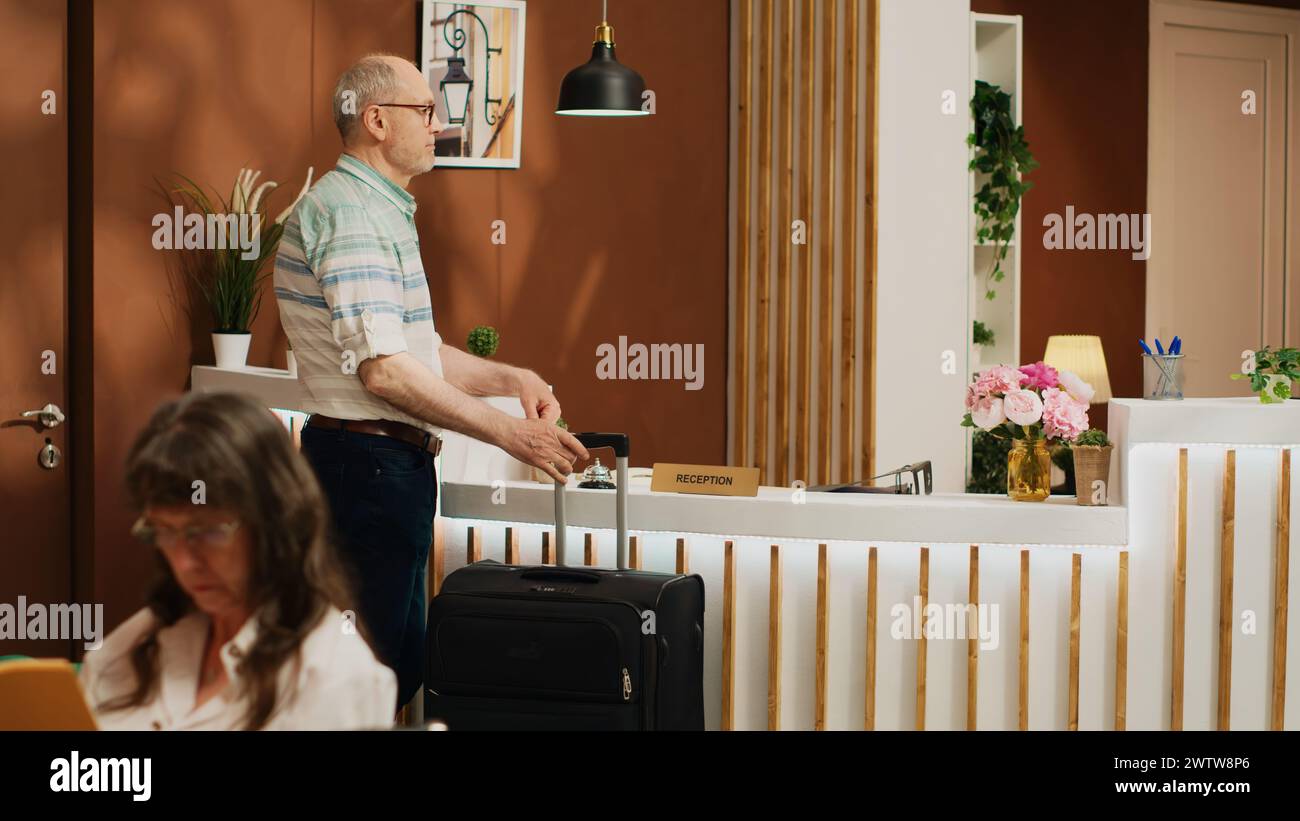 Elderly guest arrives in hotel lobby, greeted by skilled staff members ...