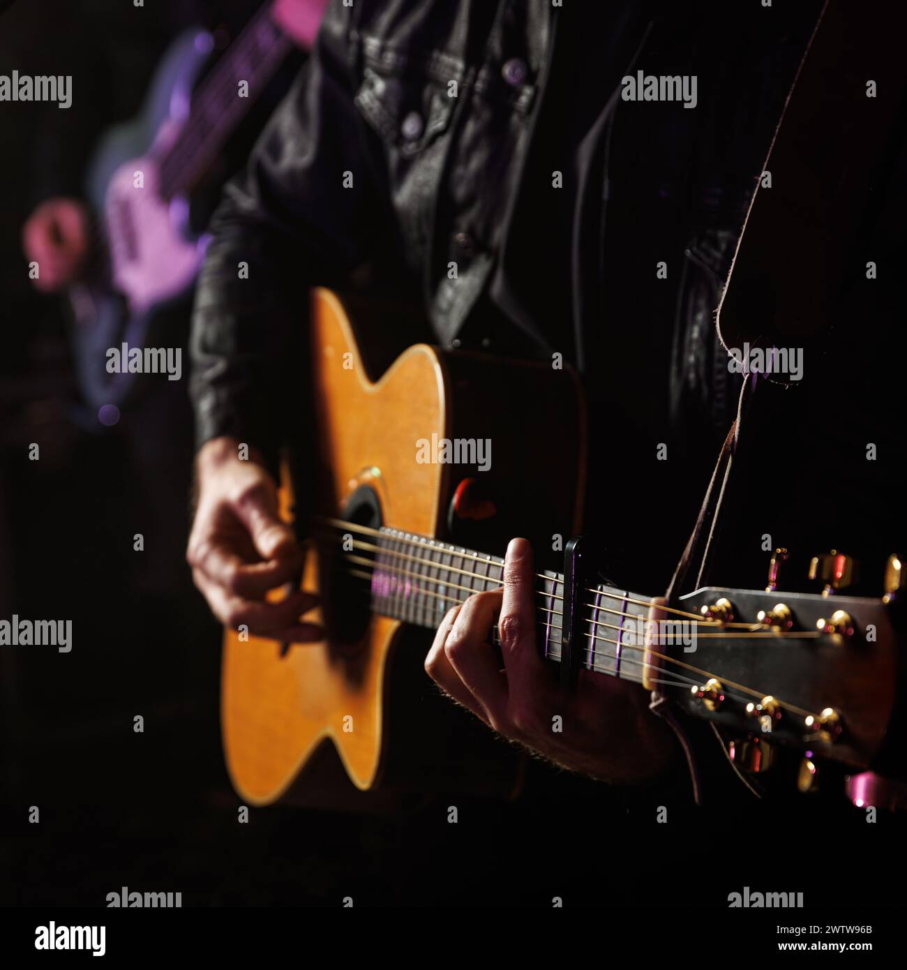 A musician plays a chord on an acoustic guitar during a performance ...