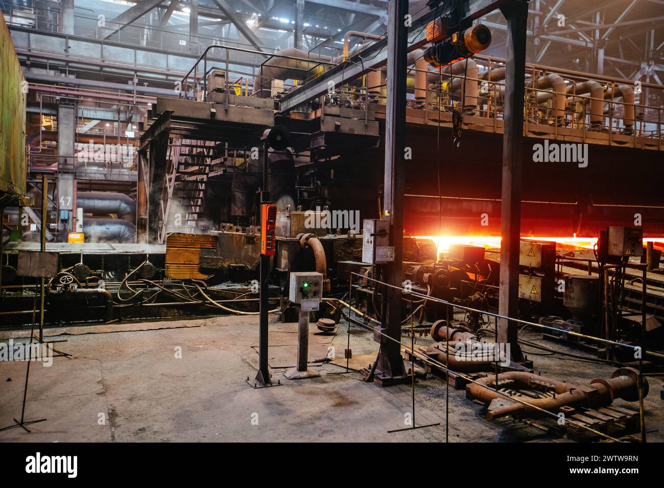 Rolled metal factory hot steel bar on conveyor moving through rollers ...
