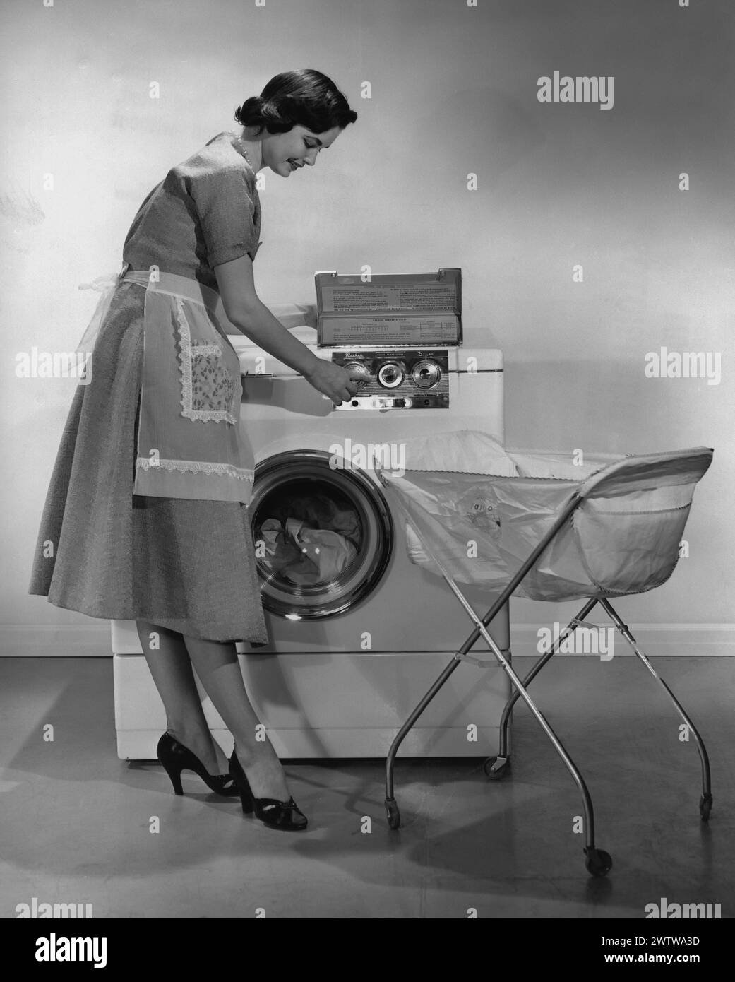 Young woman in a dress wearing an apron in high heels, standing in ...