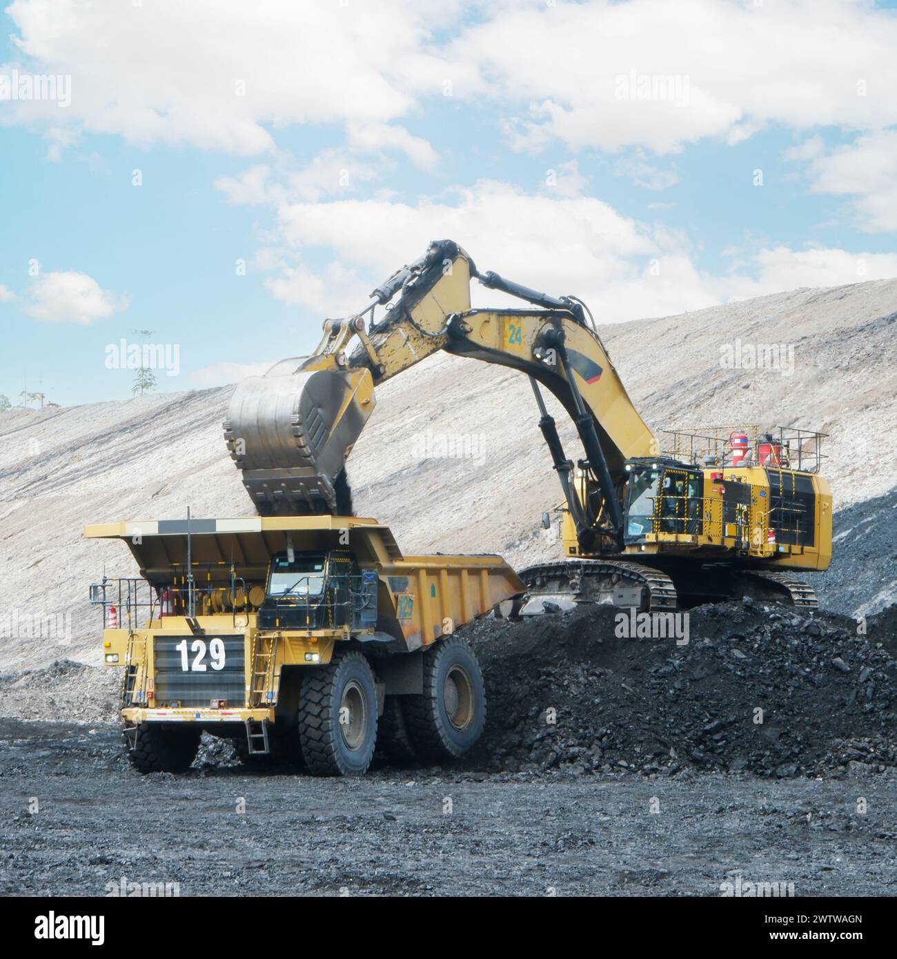 big yellow mining truck and excavator working in quarry. Loading coal ...