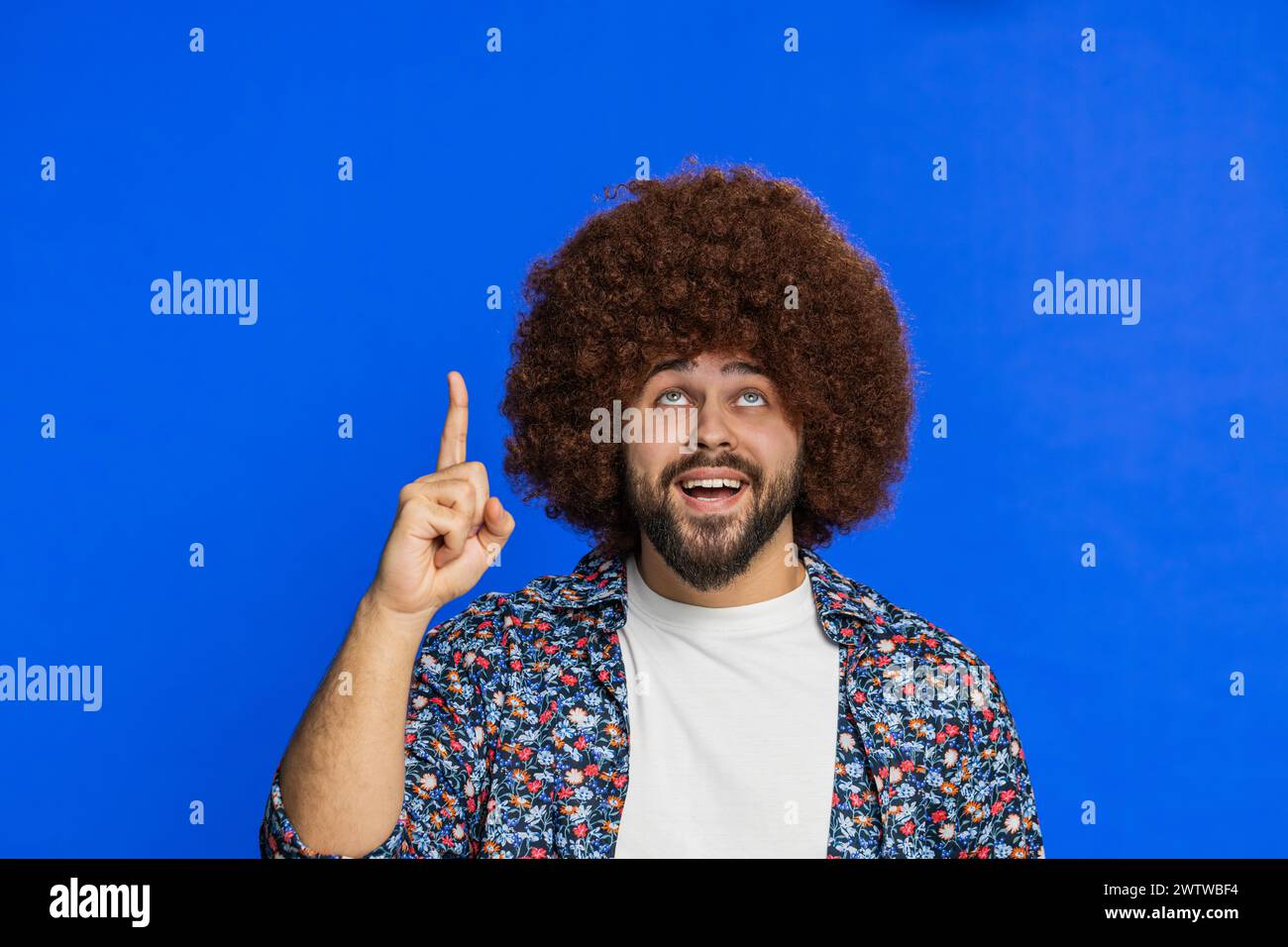 Happy man with Afro hairstyle wig showing pointing up overhead empty ...