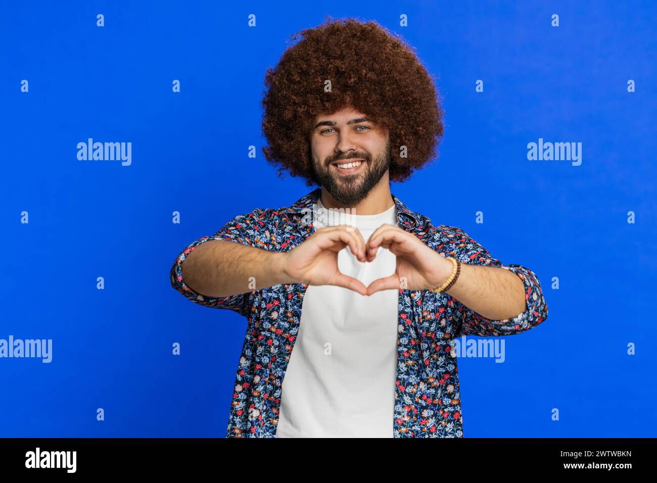 Man in love. Smiling attractive Caucasian man makes heart gesture ...