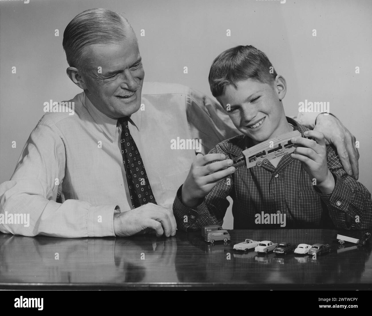 Young boy in a dress shirt sitting at the desk shares a moment with his ...
