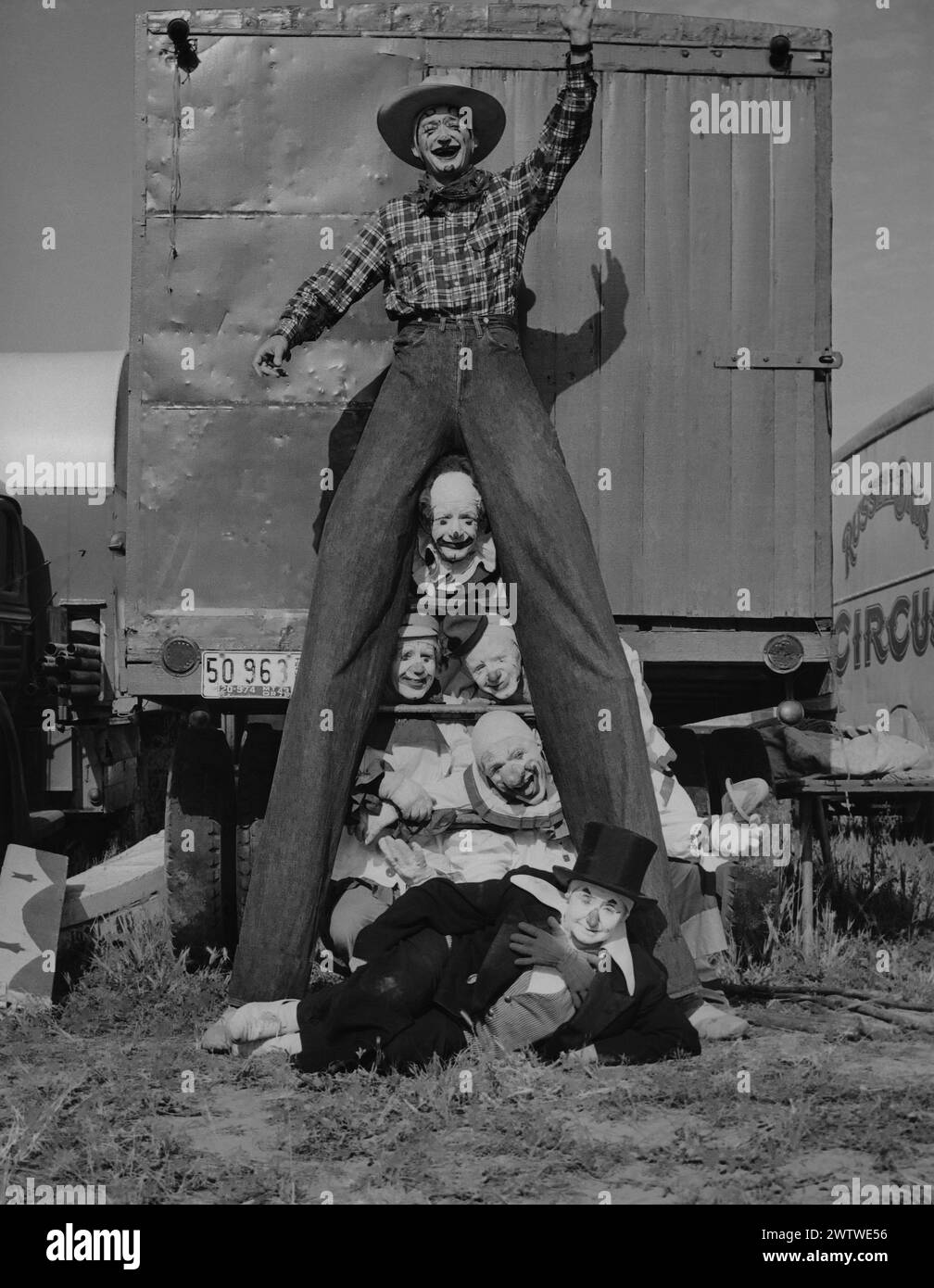 Outdoor shot of a group of clowns and this stilt man with long legs ...