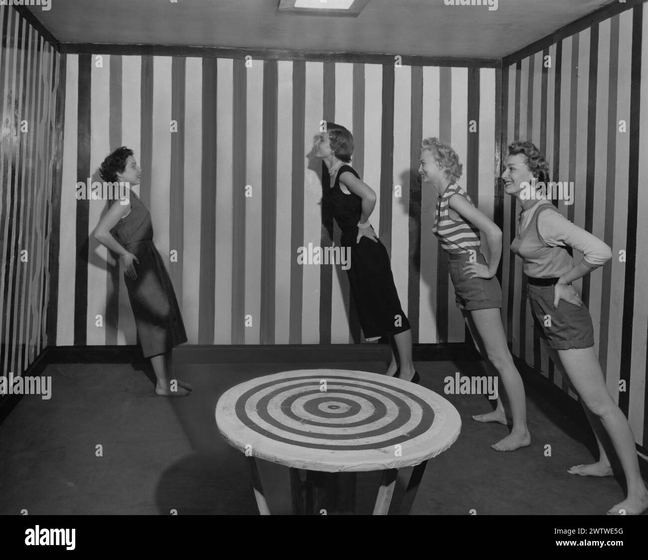 Group of four young women standing in a fun house crazy room which ...