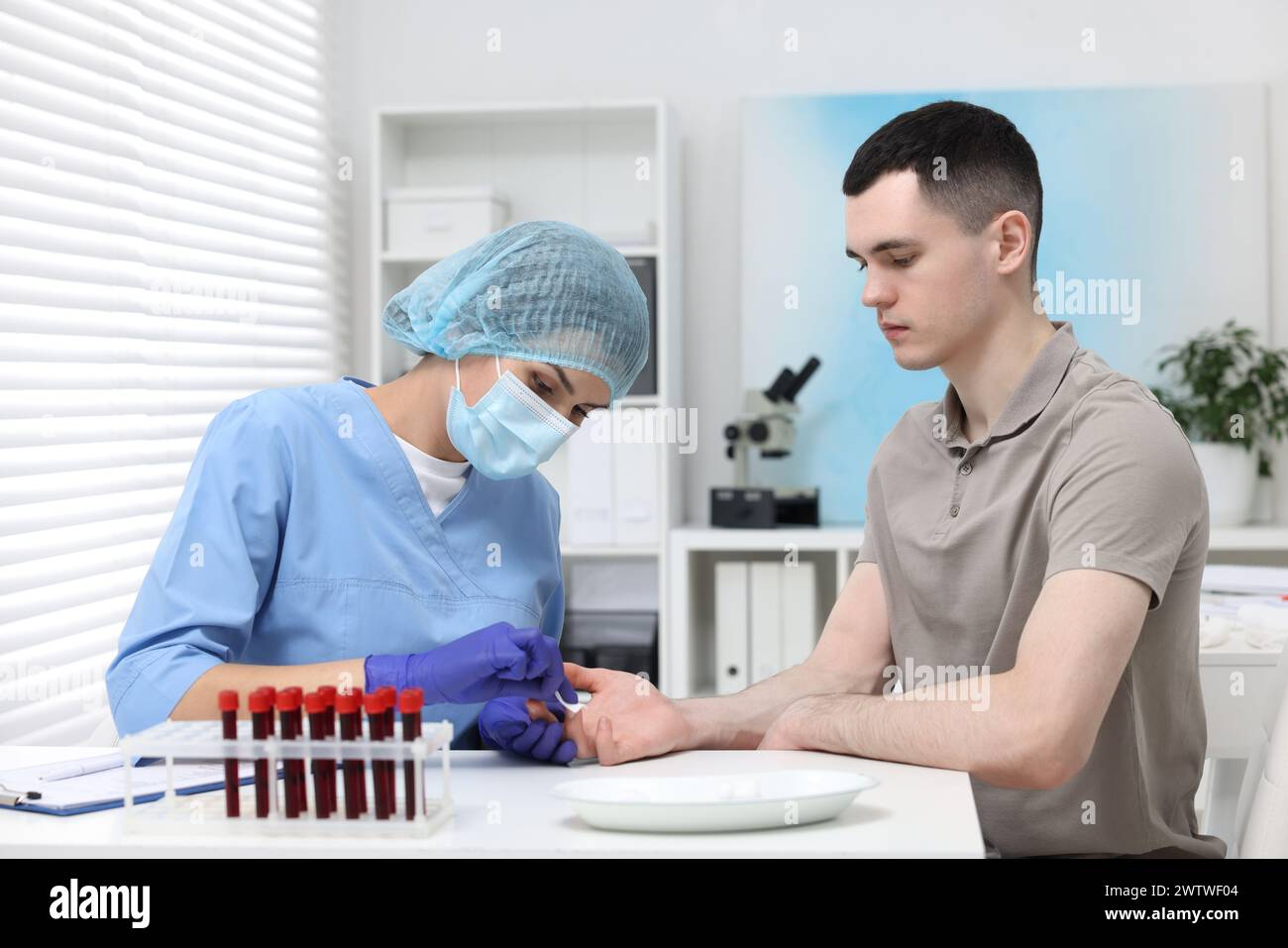Laboratory testing. Doctor taking blood sample from patient at white ...