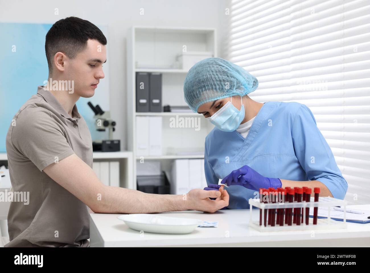 Laboratory testing. Doctor taking blood sample from patient at white ...