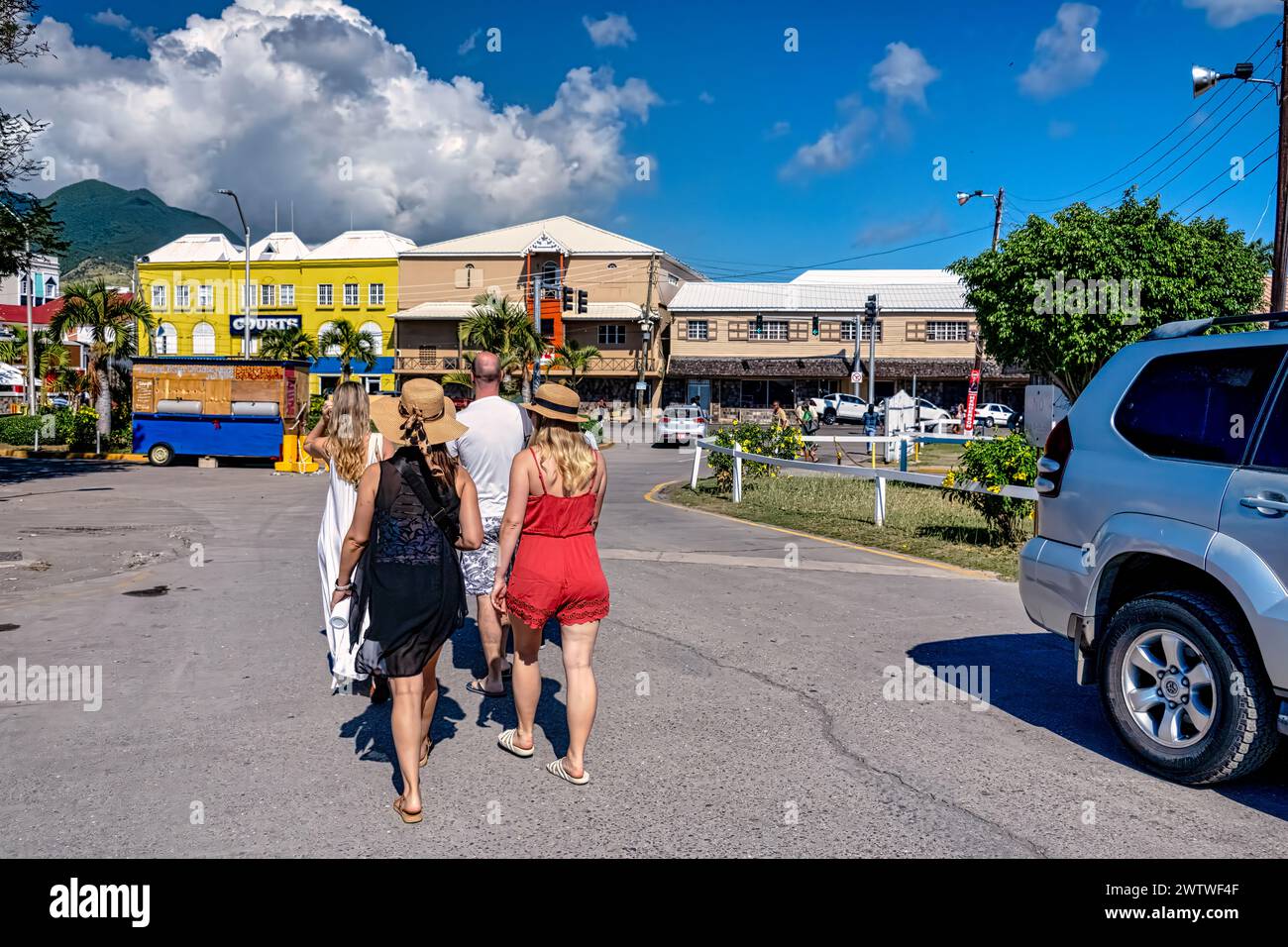 A group of tourists approach a cluster of colonial buildings under a ...
