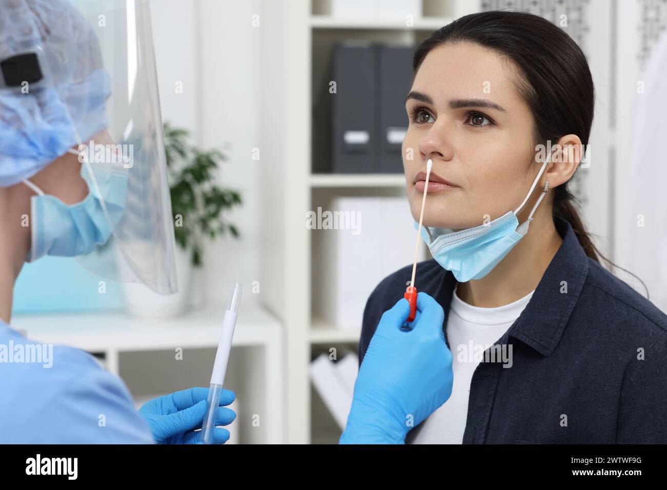 Laboratory testing. Doctor in uniform taking sample from patient's nose ...