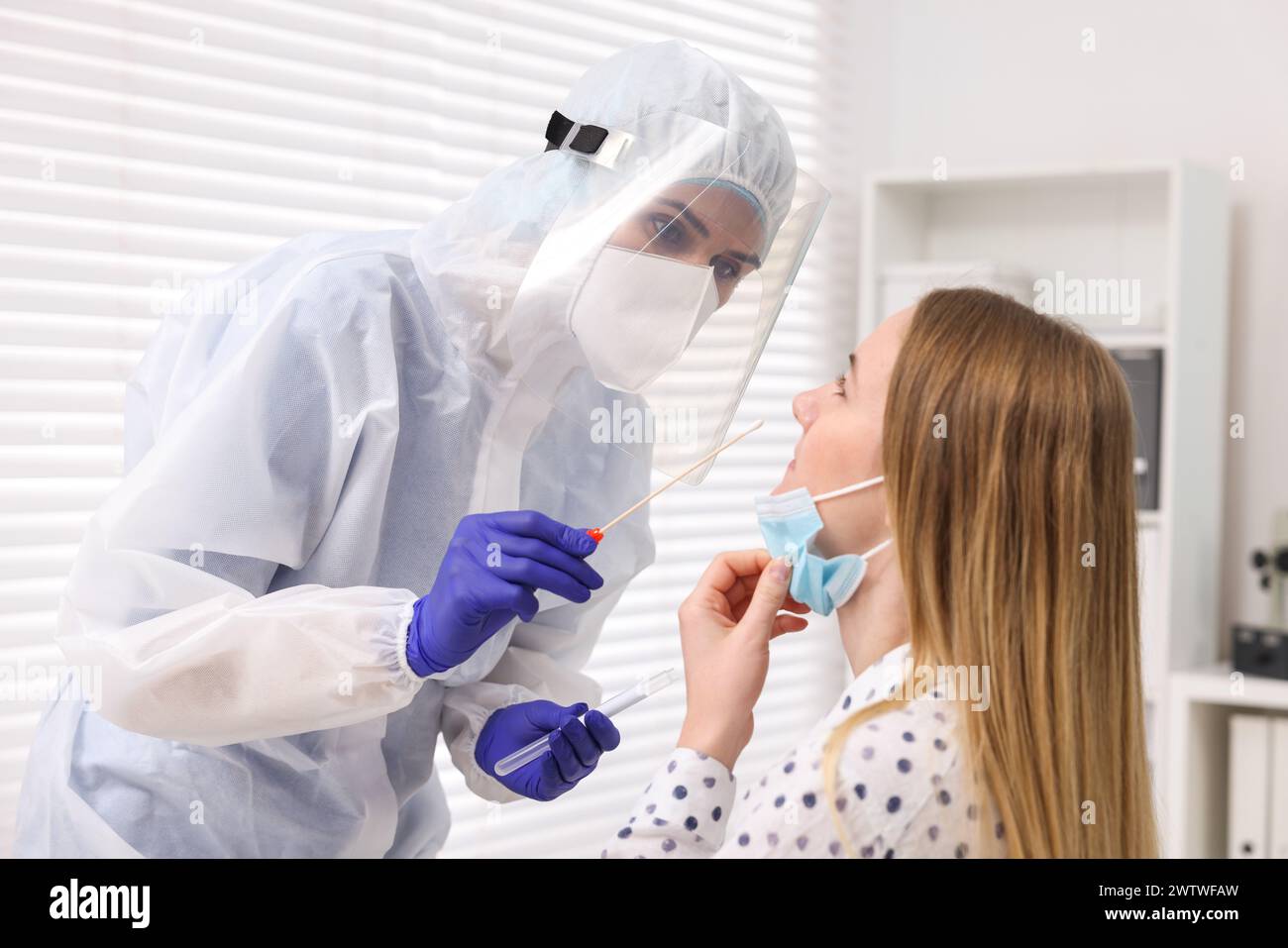 Laboratory testing. Doctor in uniform taking sample from patient's nose ...
