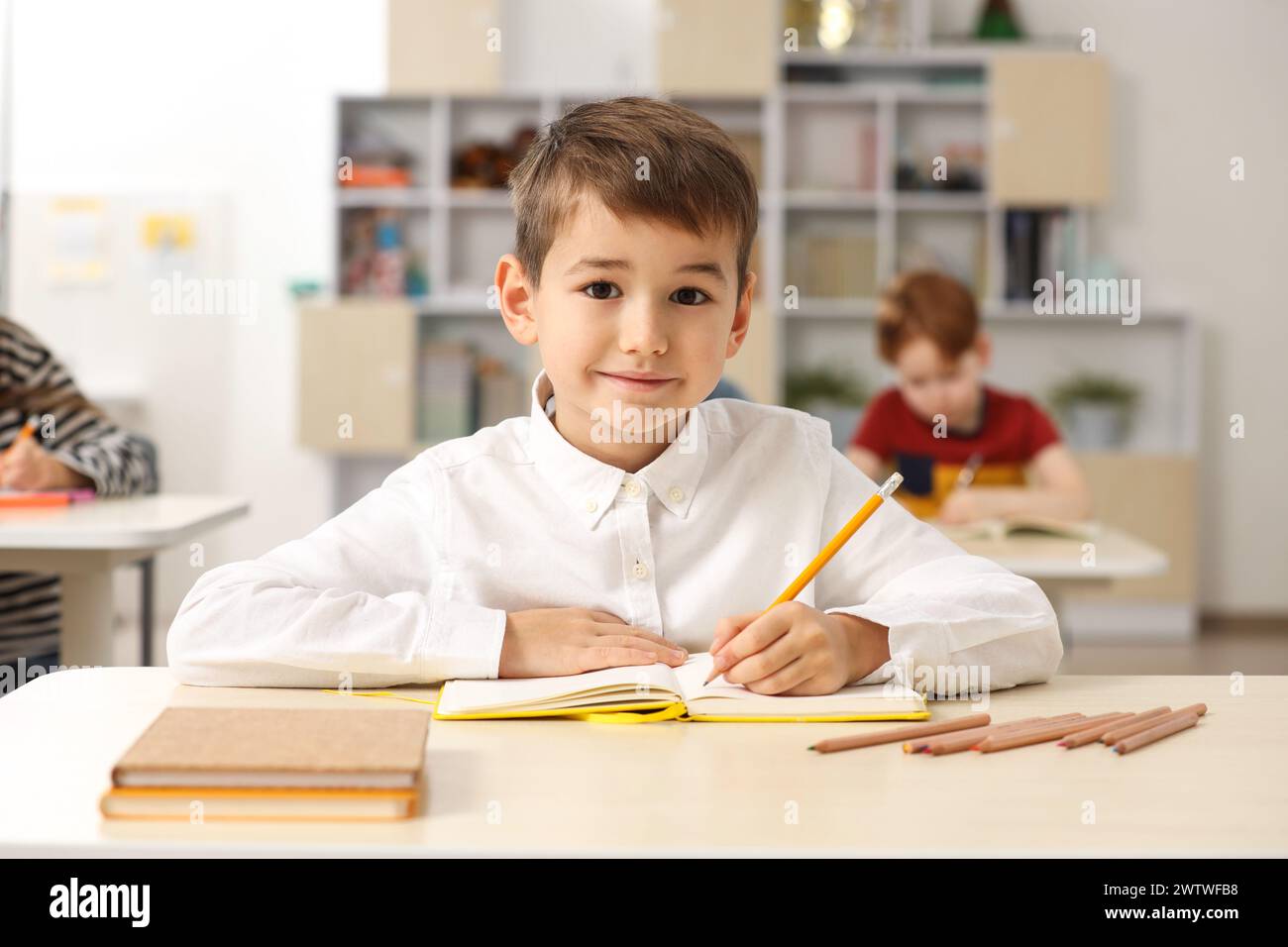 Portrait of cute little boy studying in classroom at school Stock Photo ...