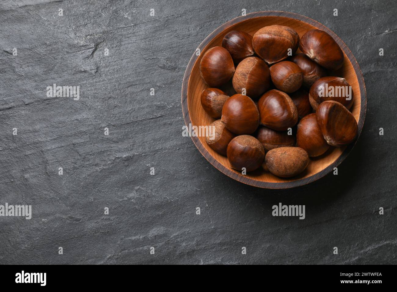Roasted edible sweet chestnuts in bowl on grey textured table, top view ...