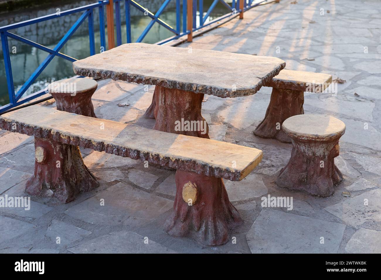 Stone table and stools set by a serene water body Stock Photo - Alamy
