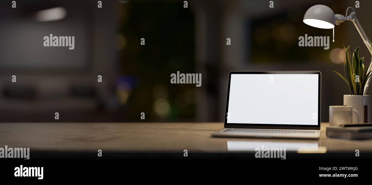 A home office at night, a white-screen laptop computer mockup on a ...