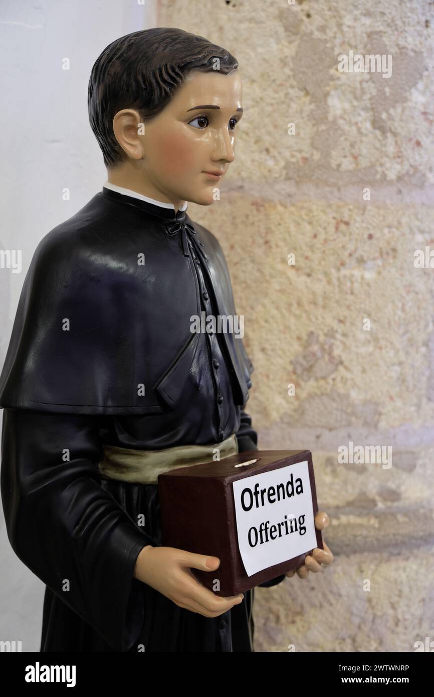The statue of an altar server holding a offering box inside of ...