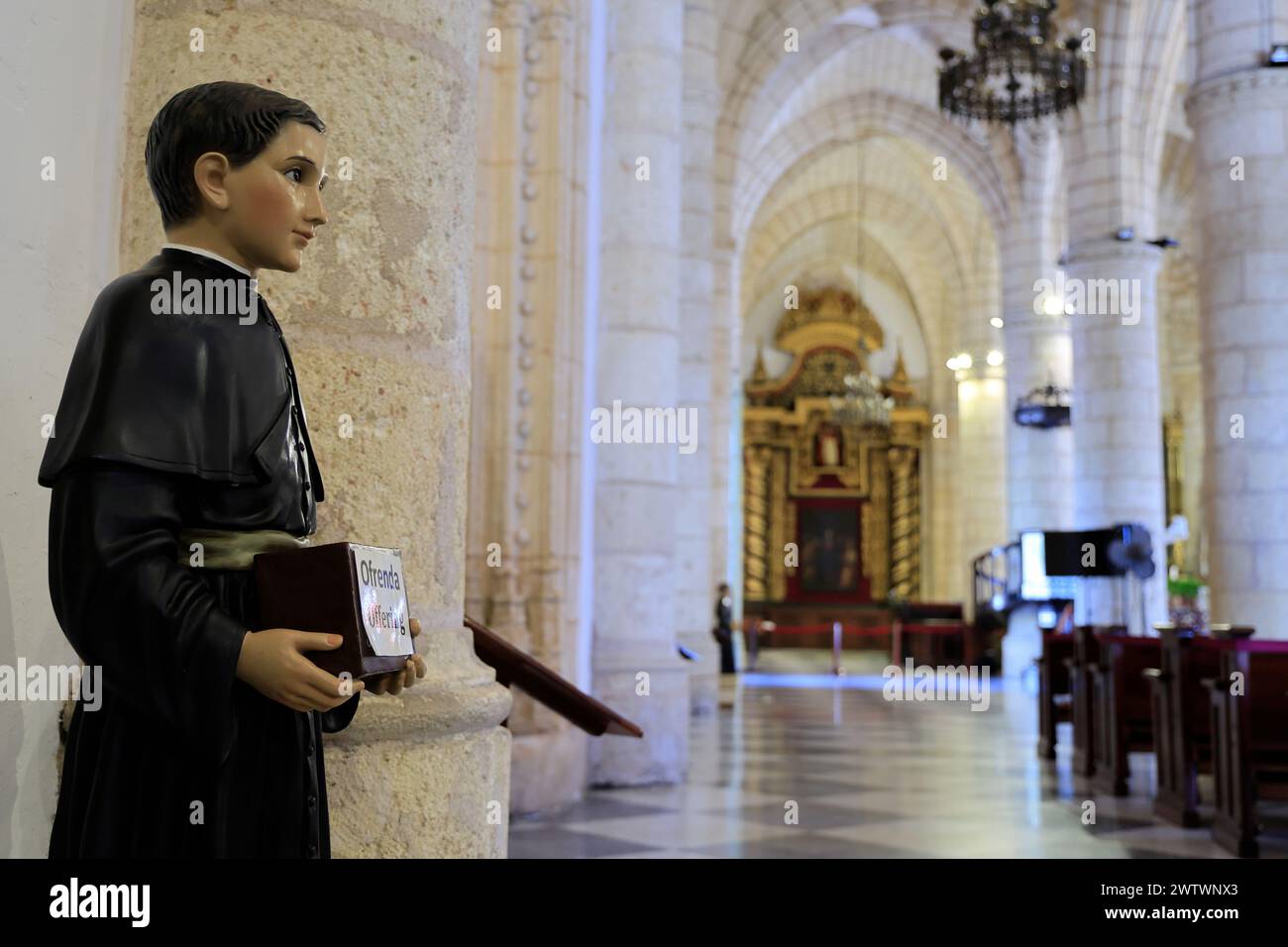 The statue of an altar server holding a offering box inside of ...