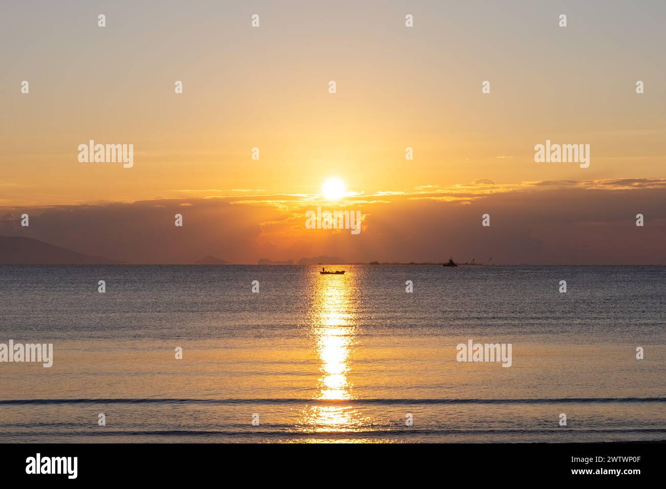 Boats on the horizon with a breathtaking sunrise Stock Photo - Alamy